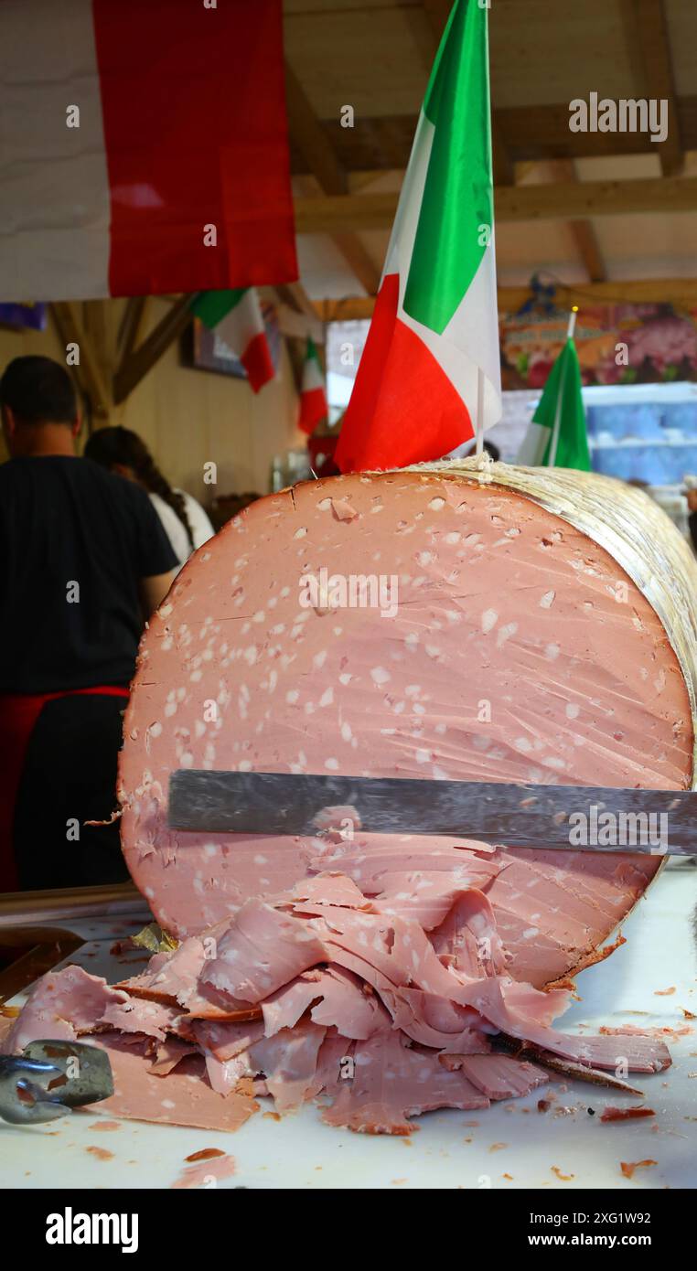 Big mortadella sliced with a long knife during the town festival Stock ...