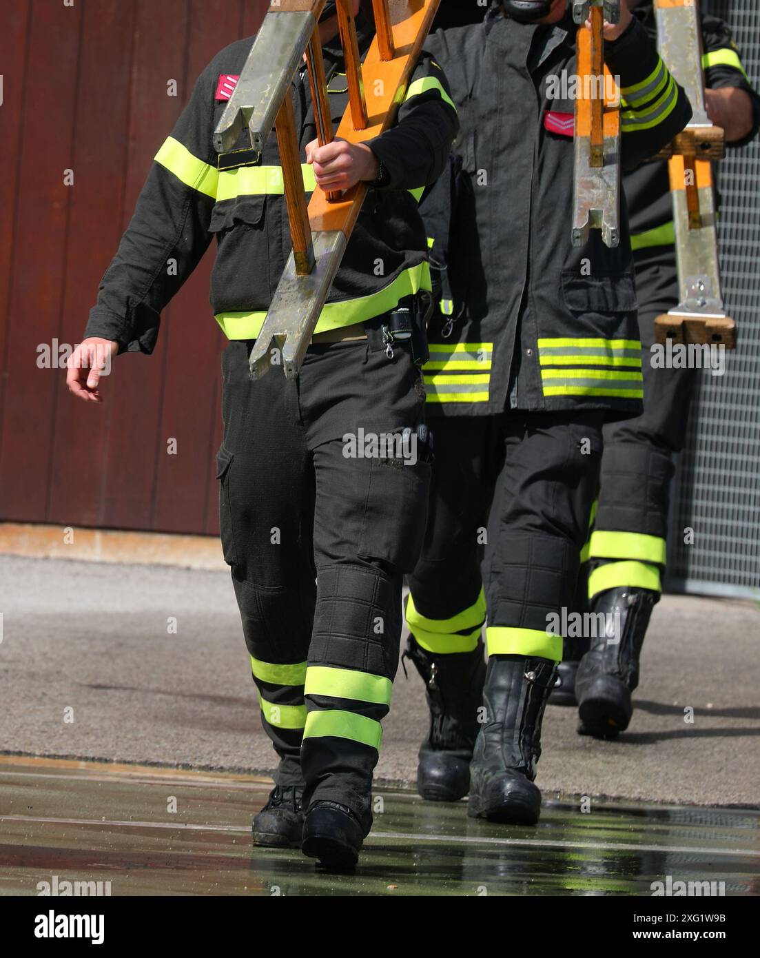 Three firefighters walk with a ladder after training at the fire ...