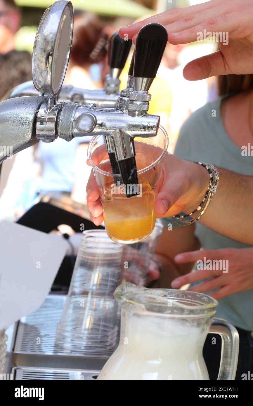 Busy bartender pouring a glass of fresh lager beer during outdoor party ...