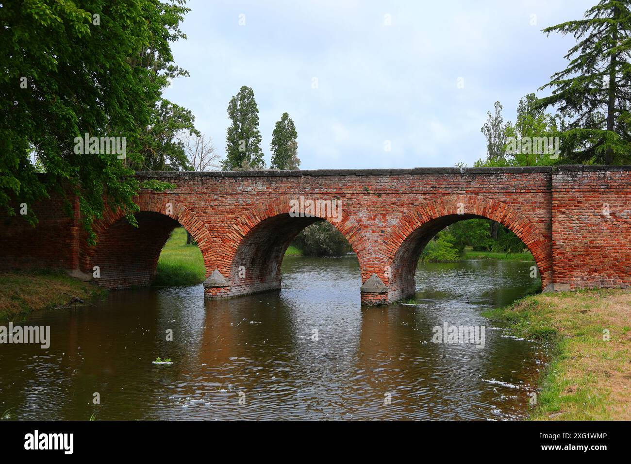 old medieval bridge made of red bricks with three arches over a canal ...