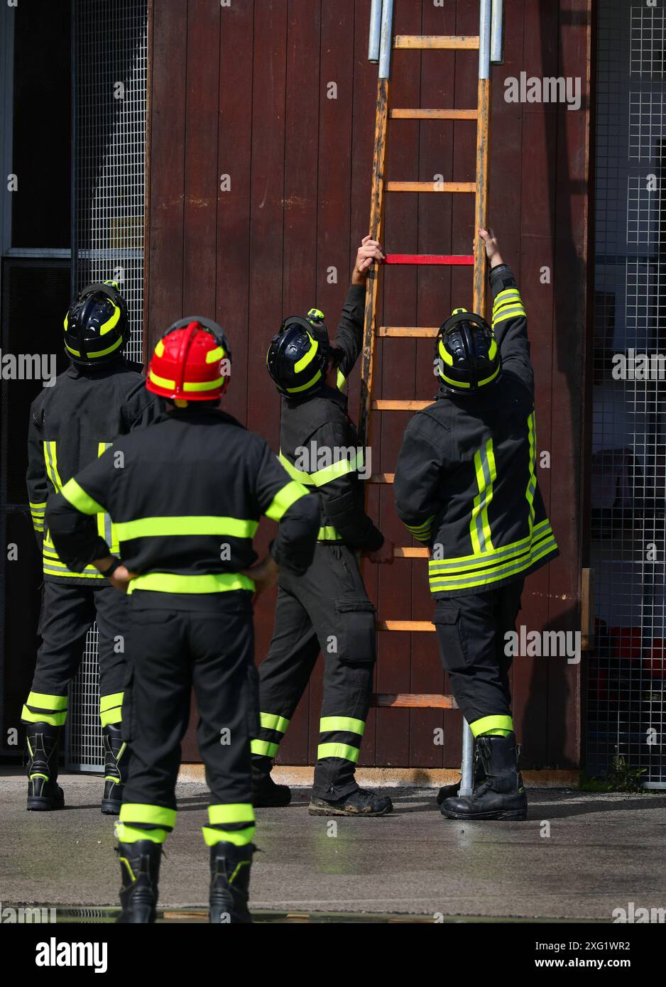 fire brigade captain with red helmet and wooden ladder during emergency ...