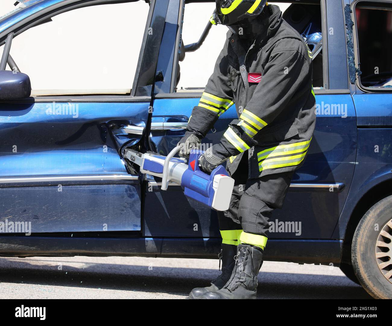 firefighter using pneumatic shears to open the jammed door of a crashed ...