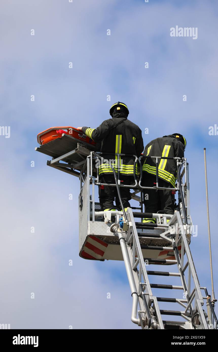 Firefighters on board an aerial platform crane with suspended stretcher ...