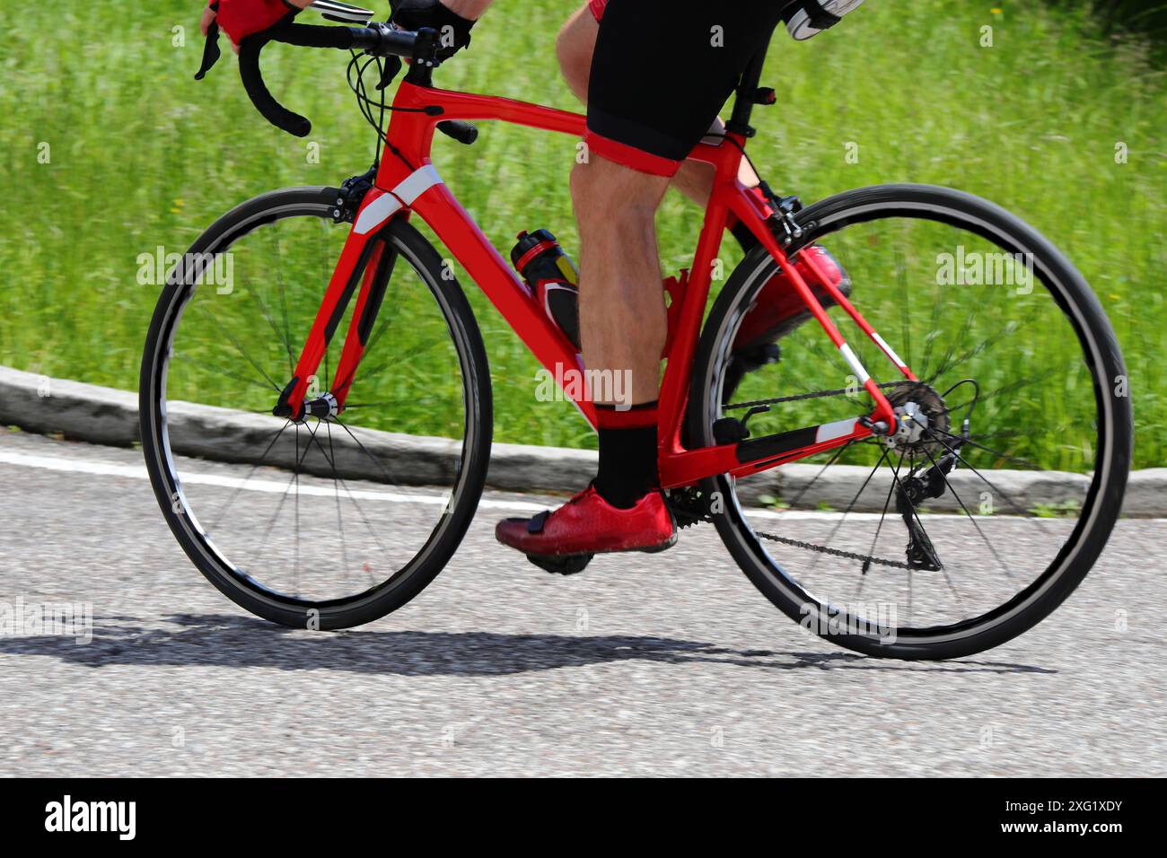 Legs of a cyclist powerfully pedaling a red road bike during a road ...