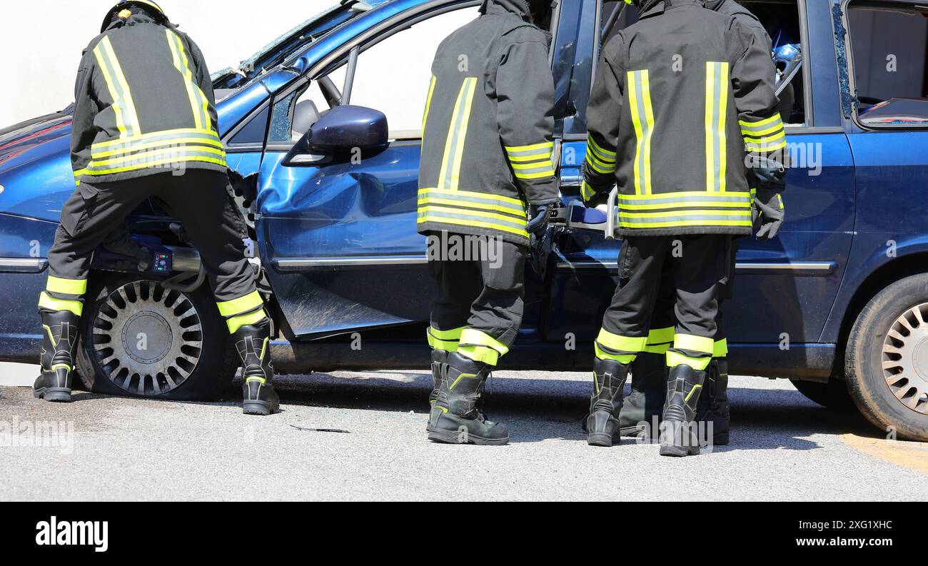 team of firefighters using hydraulic shears and jaws of life to pry ...