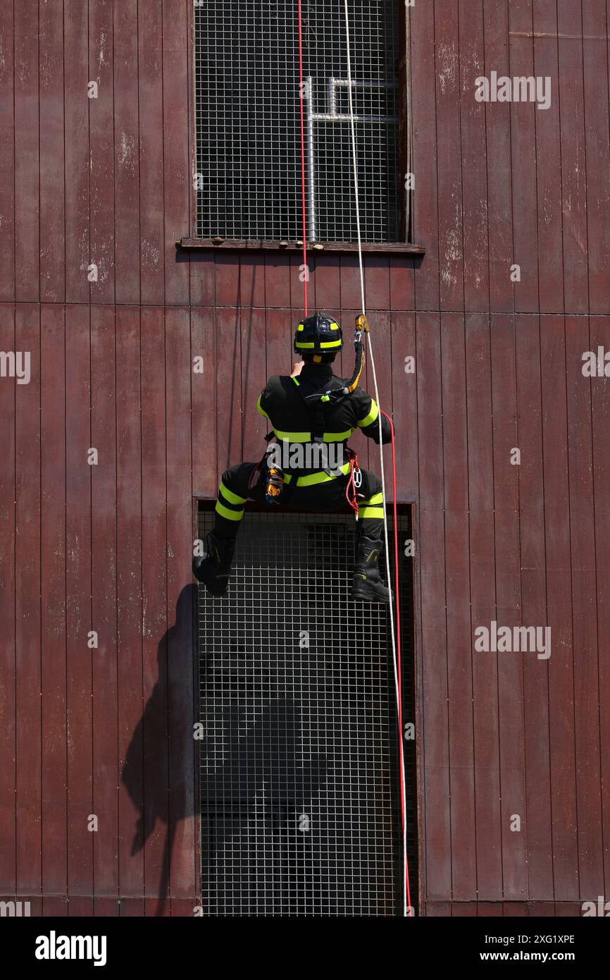 firefighter with helmet and uniform lowering himself down from the ...