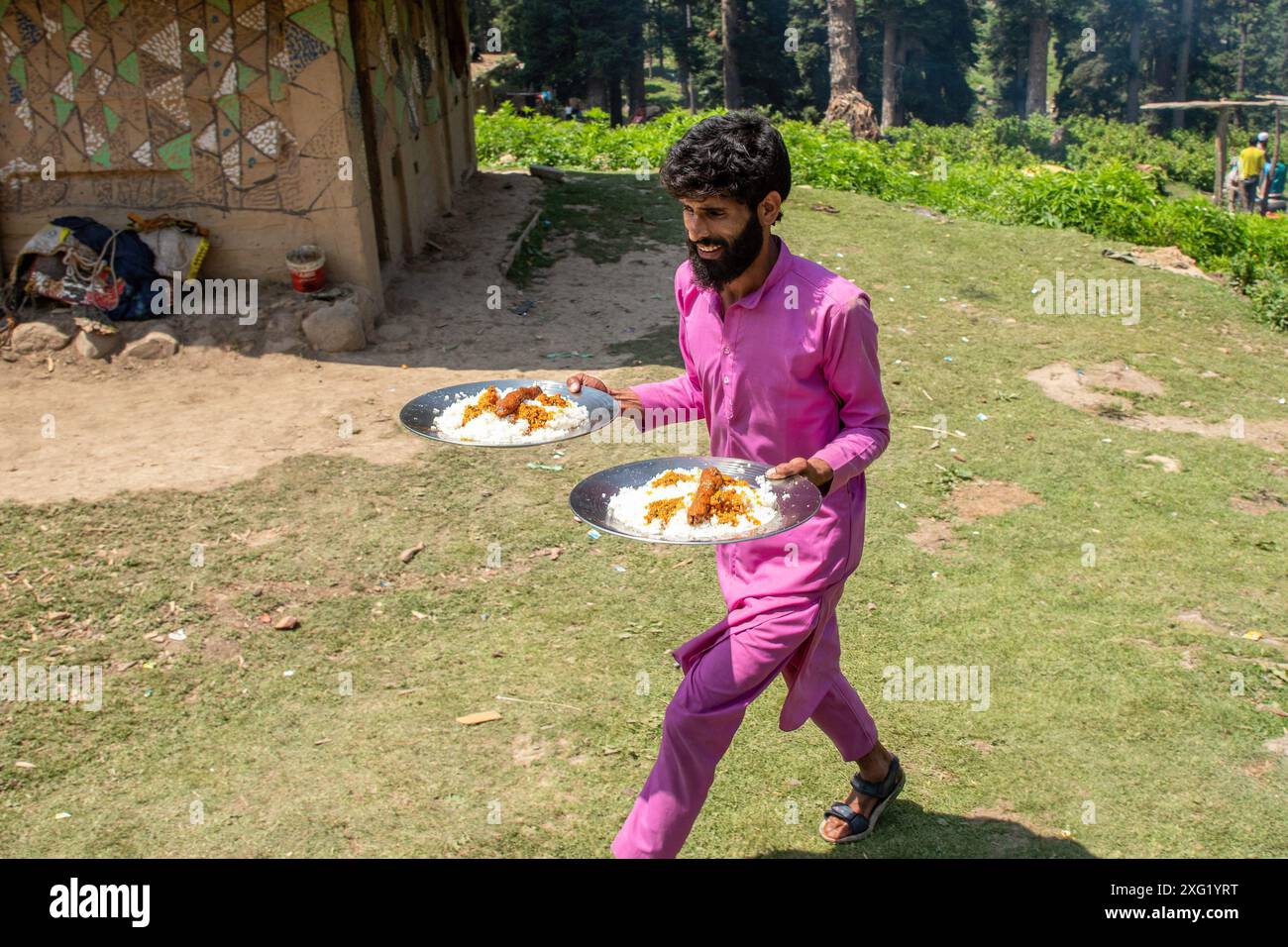 A Gujjar (nomad) man carries copper plates with rice and mutton for the ...