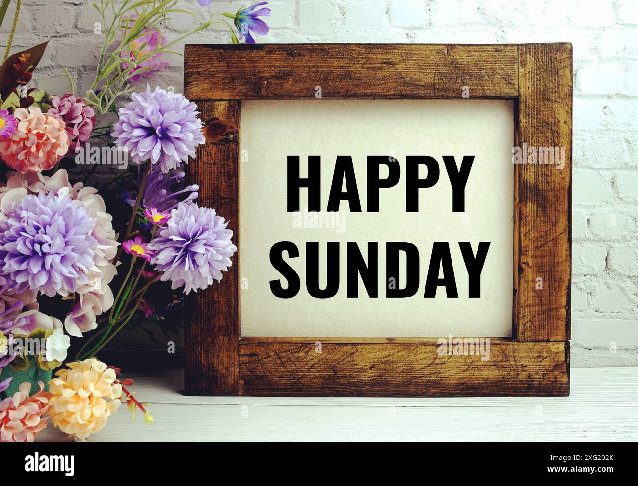Happy Sunday text with flowers decoration on white brick wall and ...