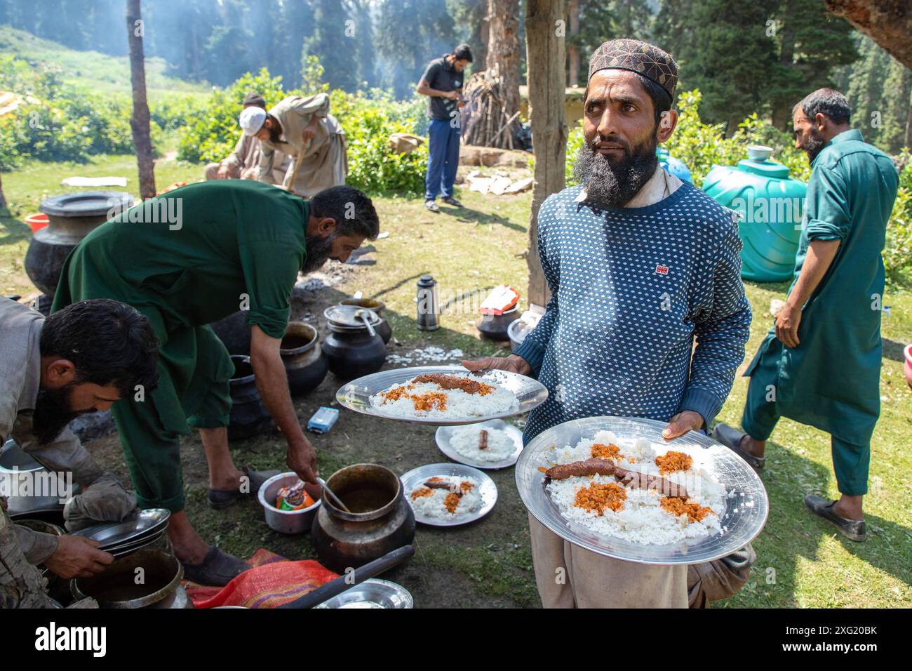 A Gujjar (nomad) man carries copper plates with rice and mutton for the ...