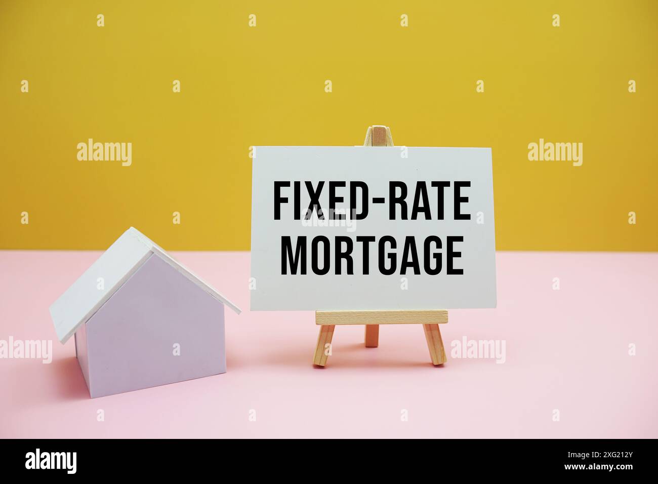 Fixed-rate mortgage text with easel and house model on yellow and pink ...