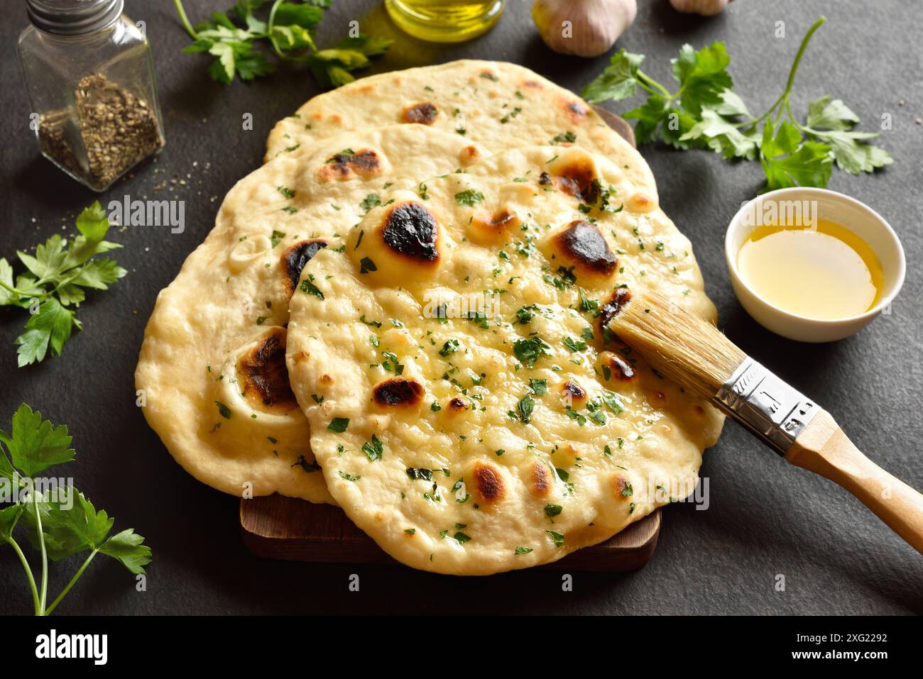 Indian naan bread with greens and garlic butter on dark stone ...