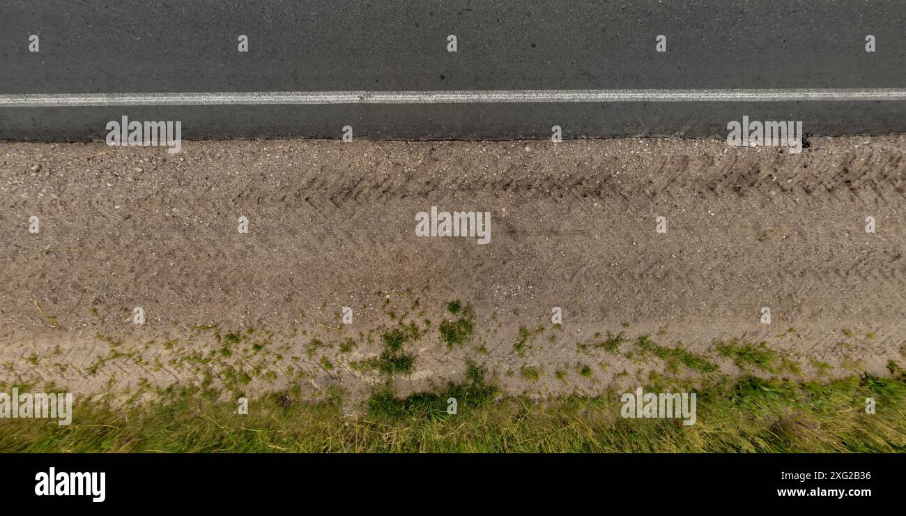 view from above on texture of asphalt road with median from gravel road ...