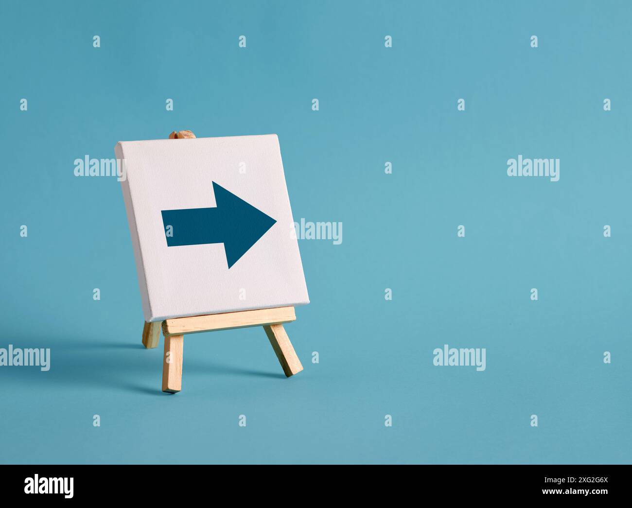 A canvas with directional arrow sign on an easel with blue background ...