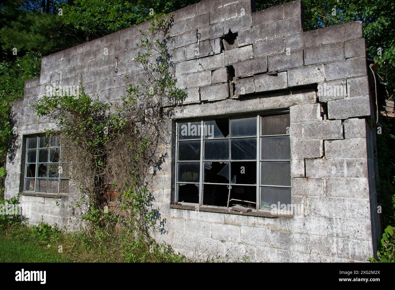 Abandoned concrete block building with crumbling wall and broken glass ...