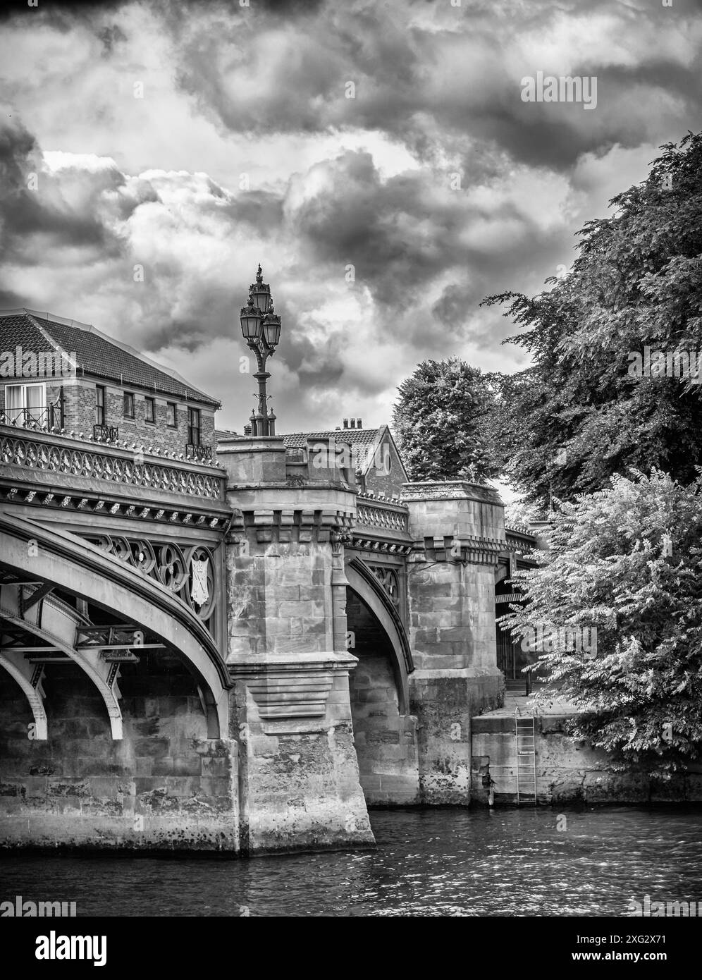 A historic stone bridge with ornate metalwork and towers span a river ...
