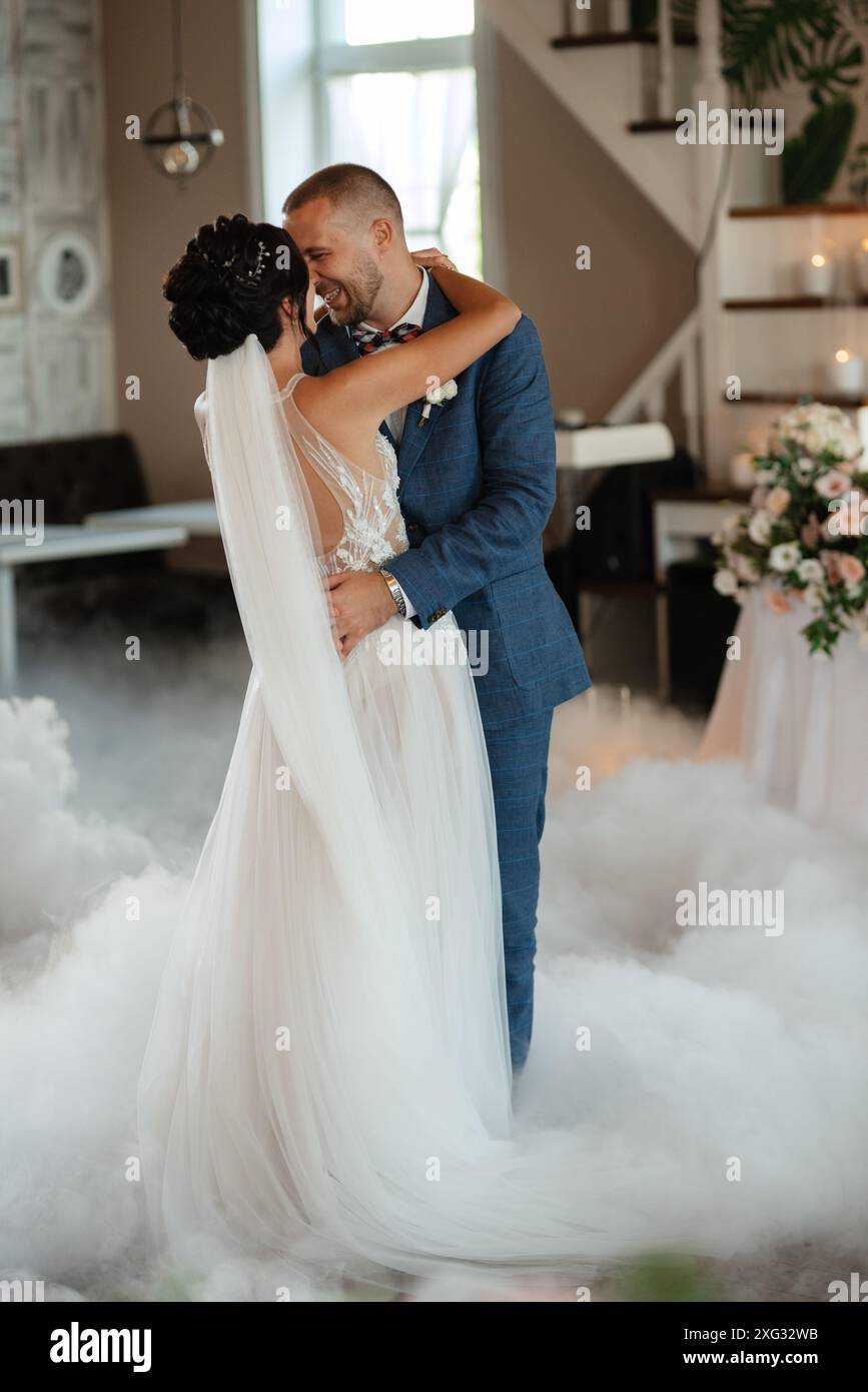 the first dance of the bride and groom inside a restaurant with heavy ...