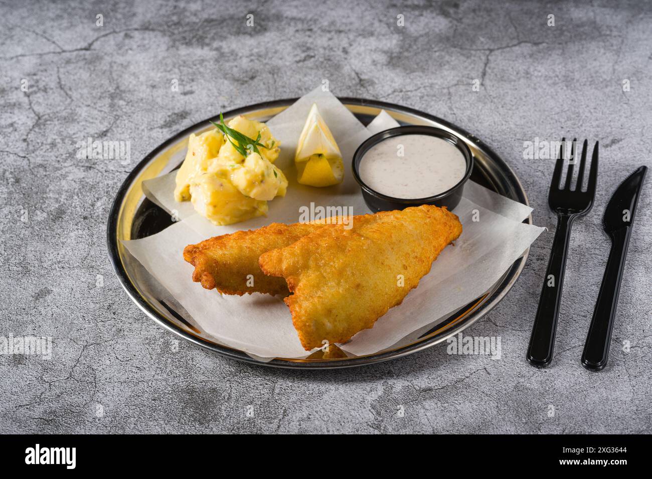 Deep fried coated fish fillet with potato salad on stone table Stock ...
