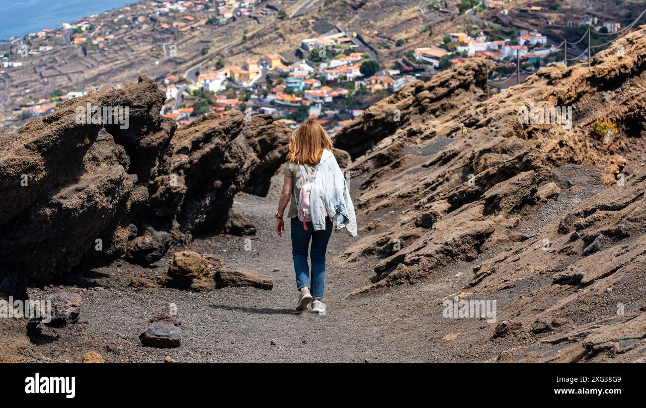 Female tourist on her back walking along the crater rim of the Teneguia ...