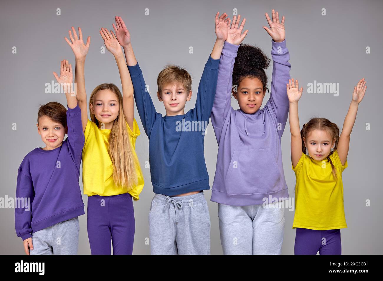 diverse happy children raising their hands, arms looking at camera ...