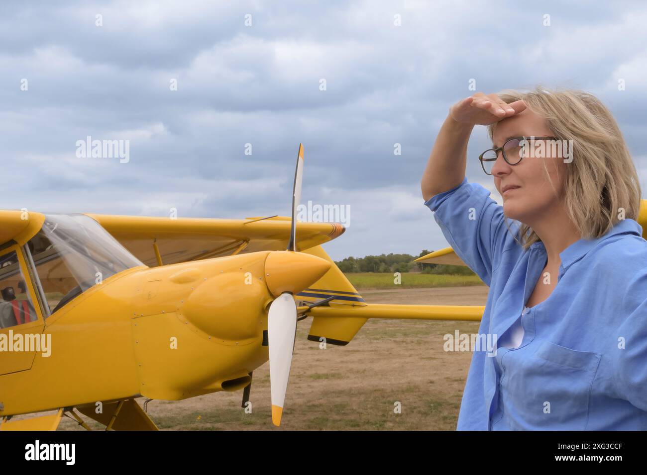 Blonde lady in glasses against the background of an airfield with a ...
