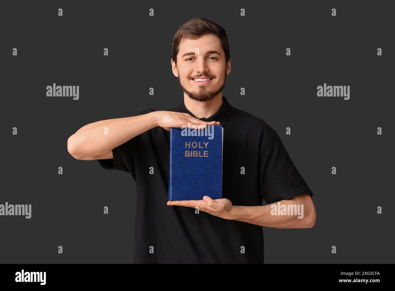 Smiling man with Holy Bible on black background Stock Photo - Alamy