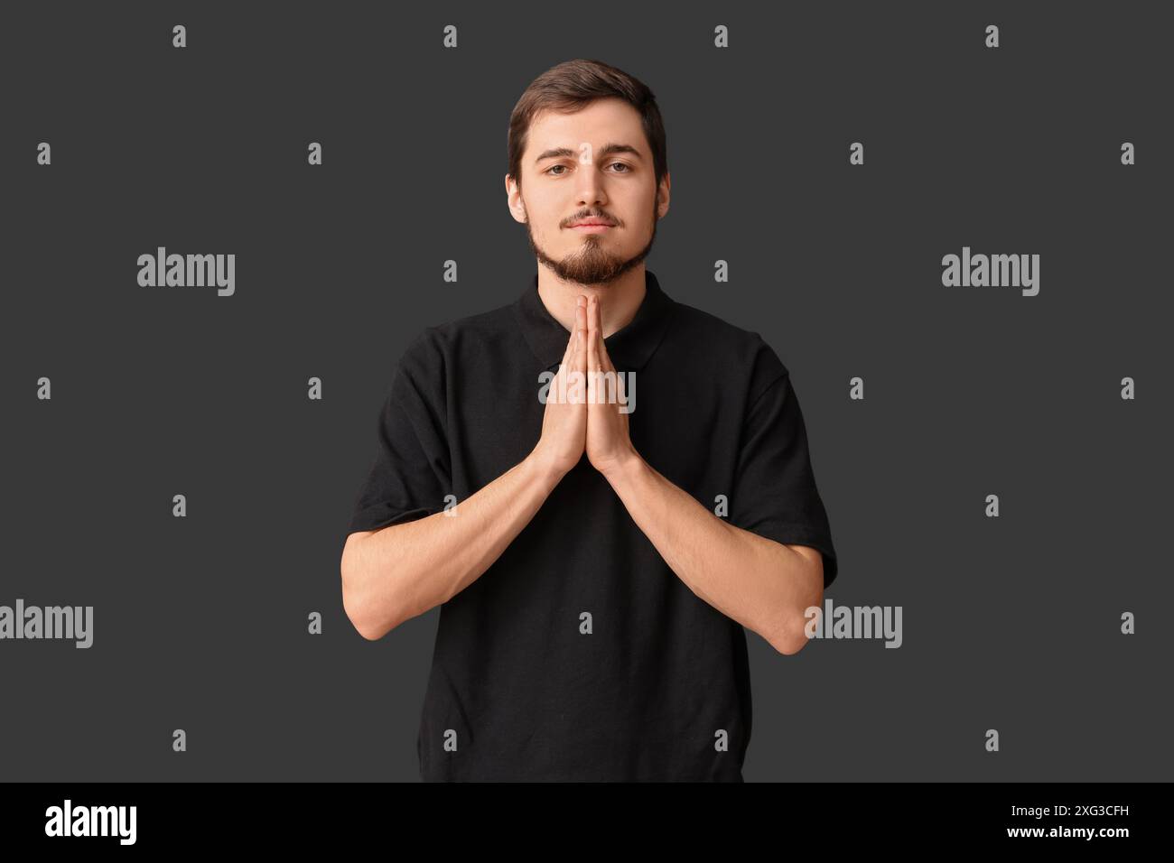 Religious man praying to God on black background Stock Photo - Alamy