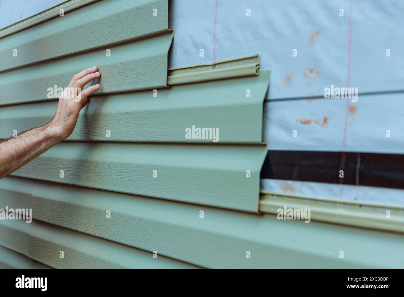 Contractor installing vinyl siding plastic panels on facade wall of new ...