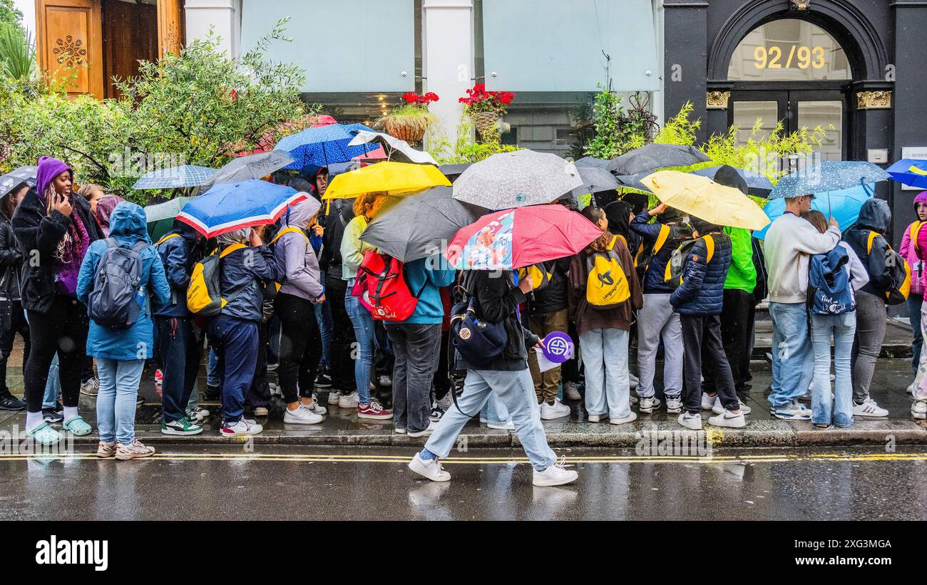 London, UK. 6th July, 2024. People shelter under umbrellas as they ...