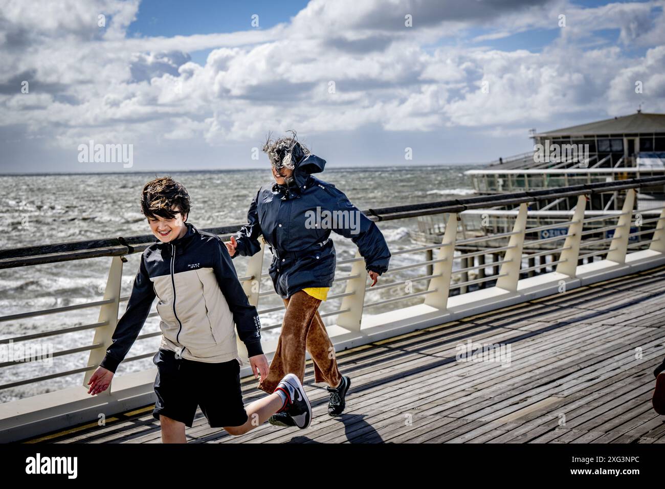 SCHEVENINGEN - Walkers have difficulty with the wind along the beach of ...