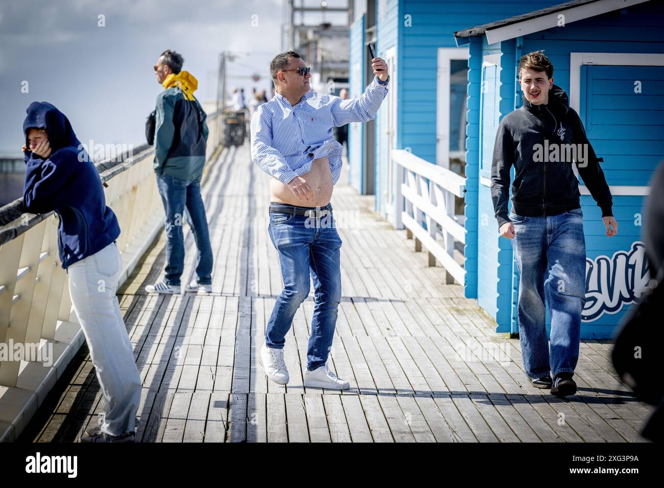 SCHEVENINGEN - Walkers have difficulty with the wind along the beach of ...