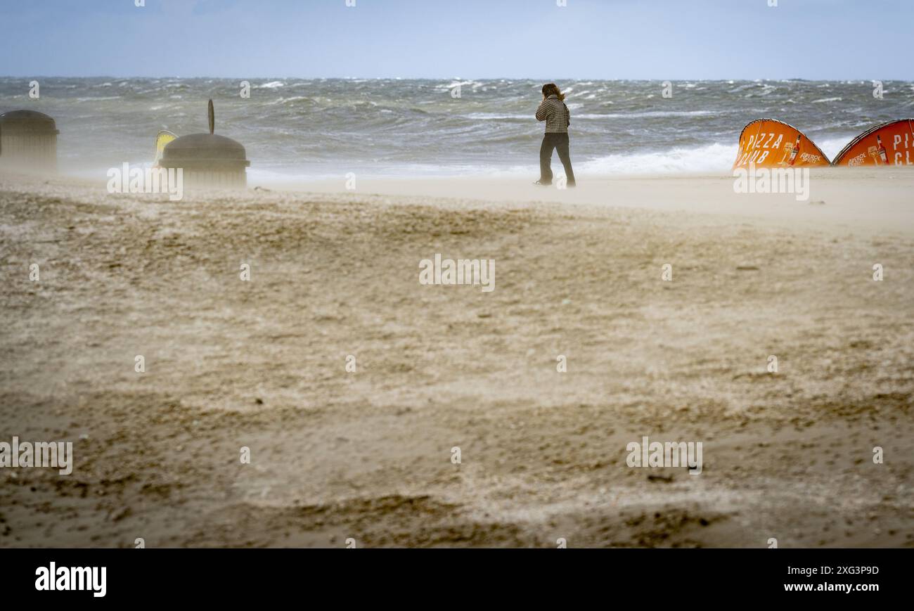 SCHEVENINGEN - Walkers have difficulty with the wind along the beach of ...