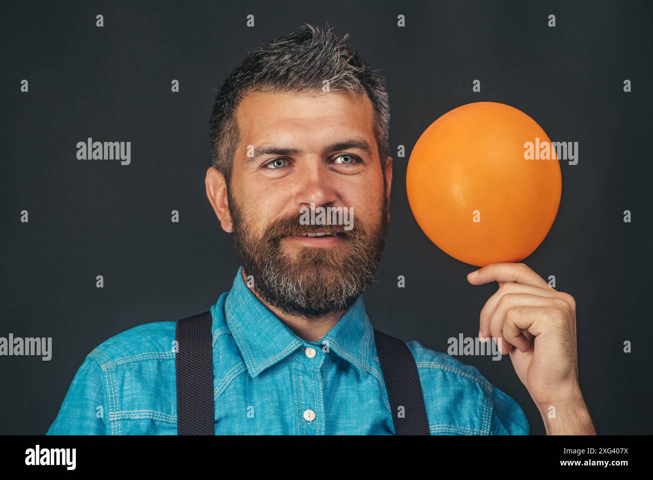 Smiling bearded man in denim shirt with orange helium balloon. Handsome ...
