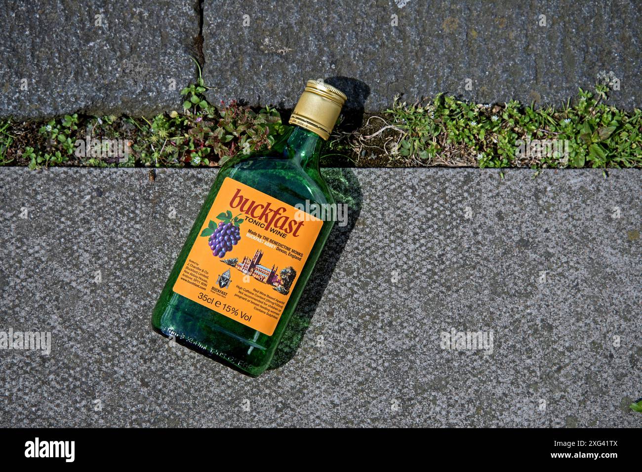 Empty half bottle of Buckfast Tonic Wine discarded on the pavement on a ...