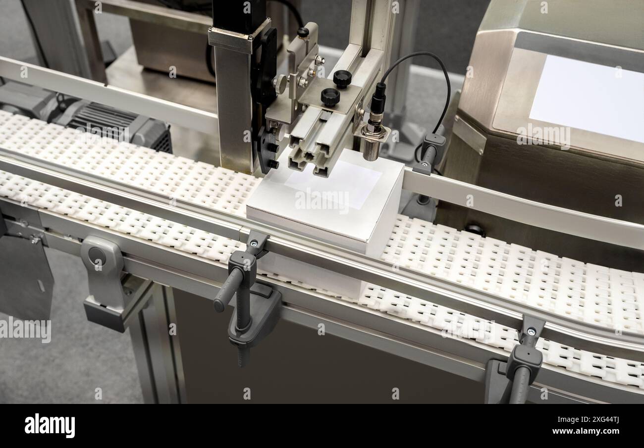 Automatic product labeling and printing solution. White cardboard box on belt of industrial ...