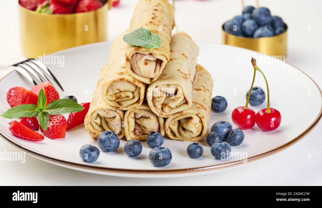 Stack of fried crepes with filling on a round plate, white table Stock ...