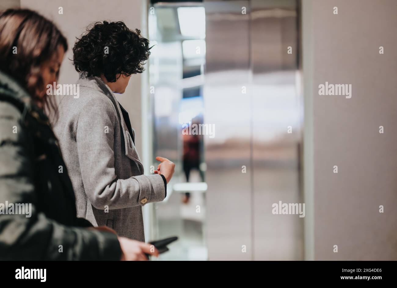 Side view of young professionals using smart phones waiting by an ...