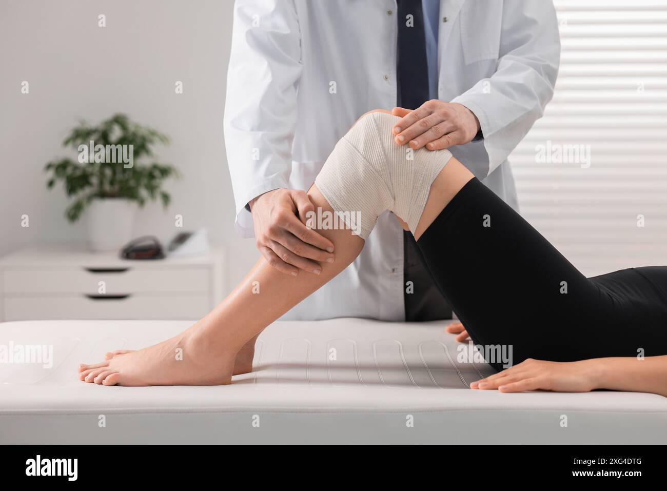 Sports injury. Doctor examining patient's knee in hospital, closeup ...