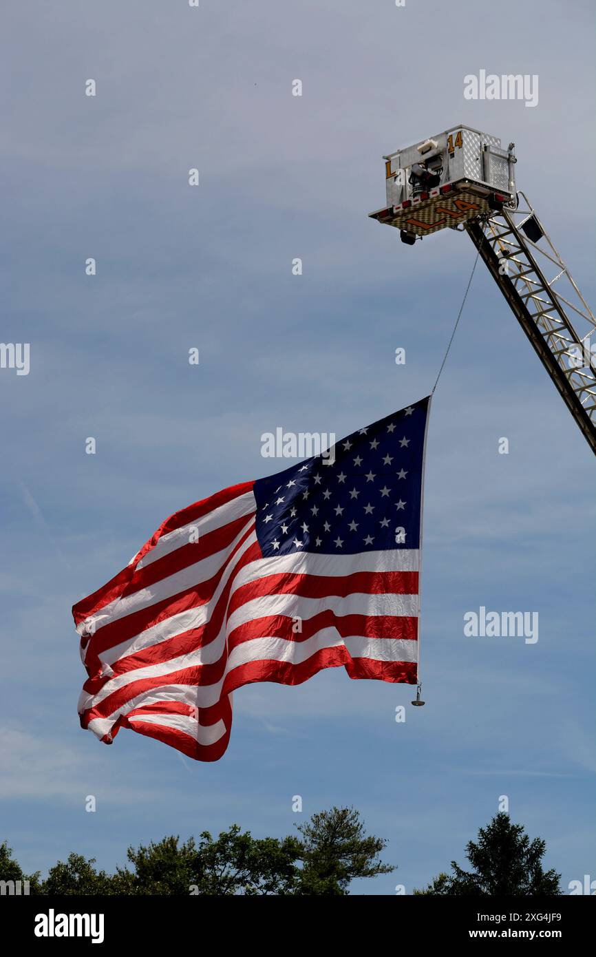 A large Amerian flag hangs from a fire departmet ladder truck at a ...