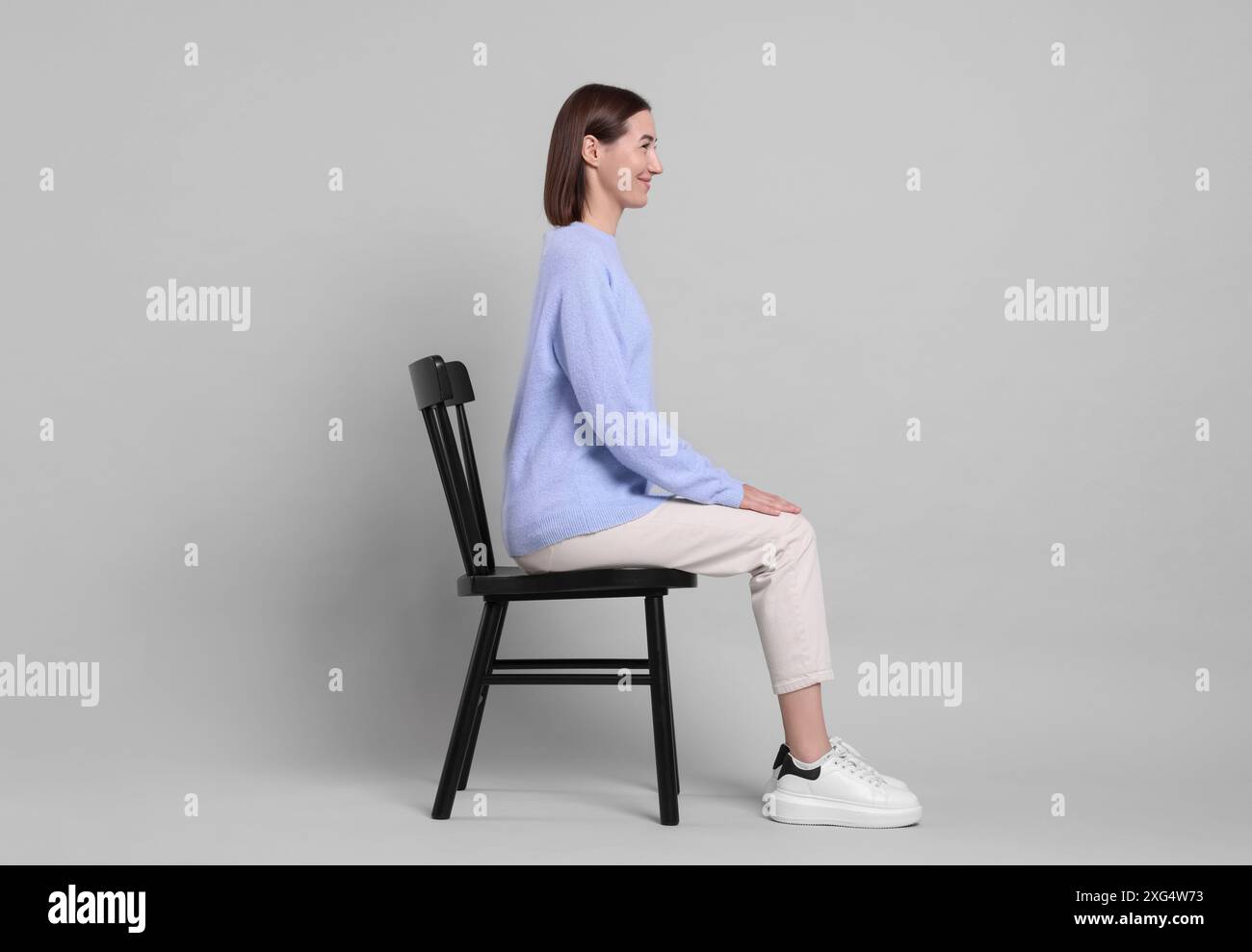 Woman with good posture sitting on chair against gray background Stock ...