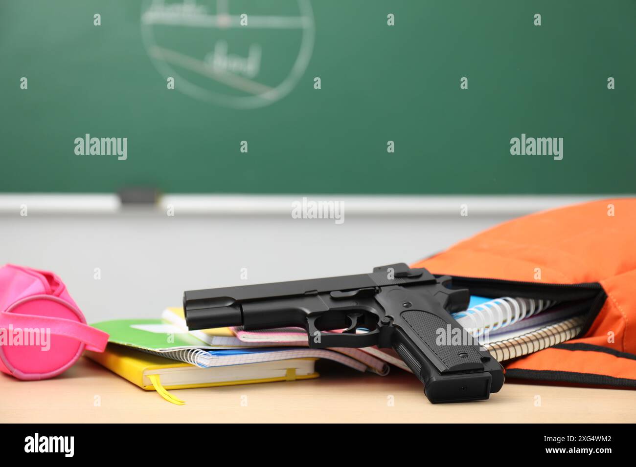 School stationery and gun on desk in classroom, closeup Stock Photo - Alamy