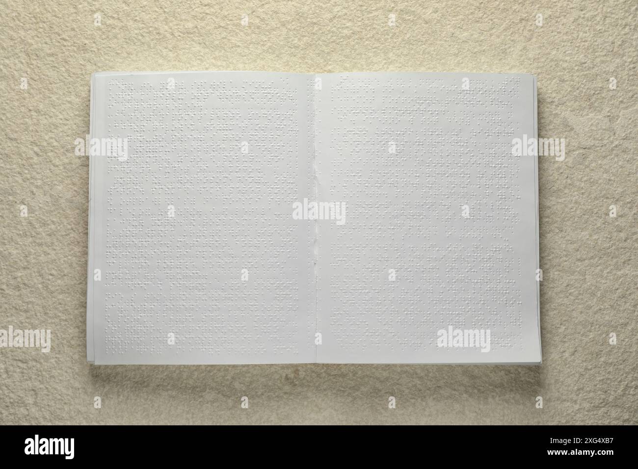 Book with Braille text on beige textured table, top view. Education and ...