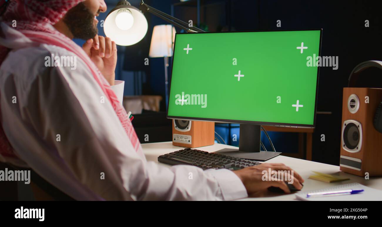 Muslim worker looking at chroma key computer screen while working from ...