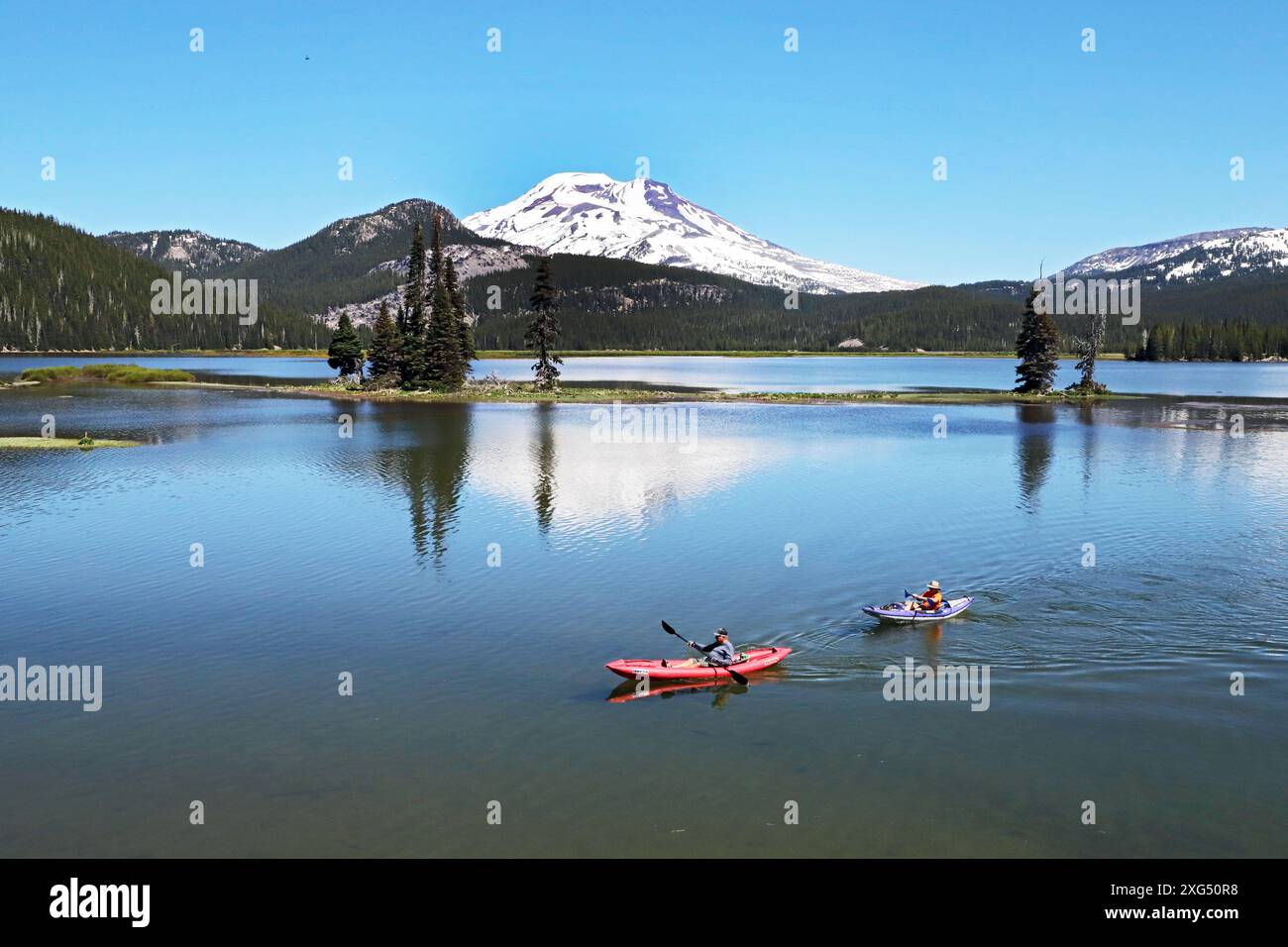 Two kayakers in kayaks navigate the beautiful waters of Sparks Lake, along the Cascade Lakes ...