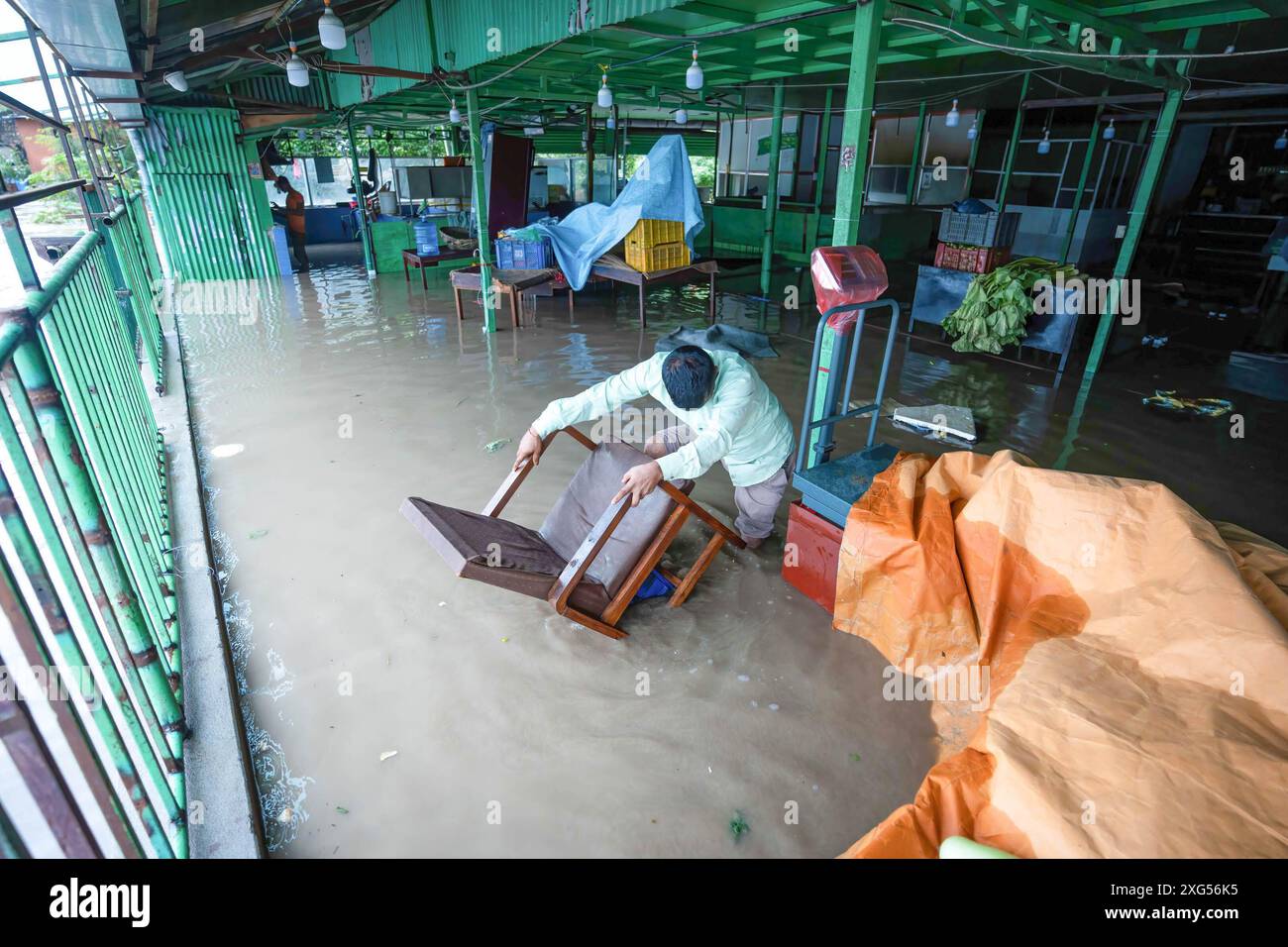 A man seen at a flooded vegetable market as a river overflows after ...