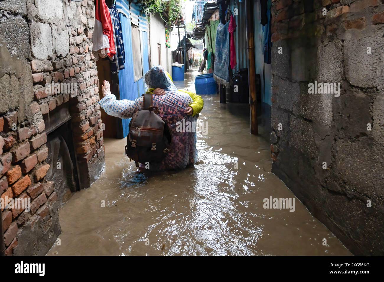A woman carrying her child passes through flooded water. After Heavy ...