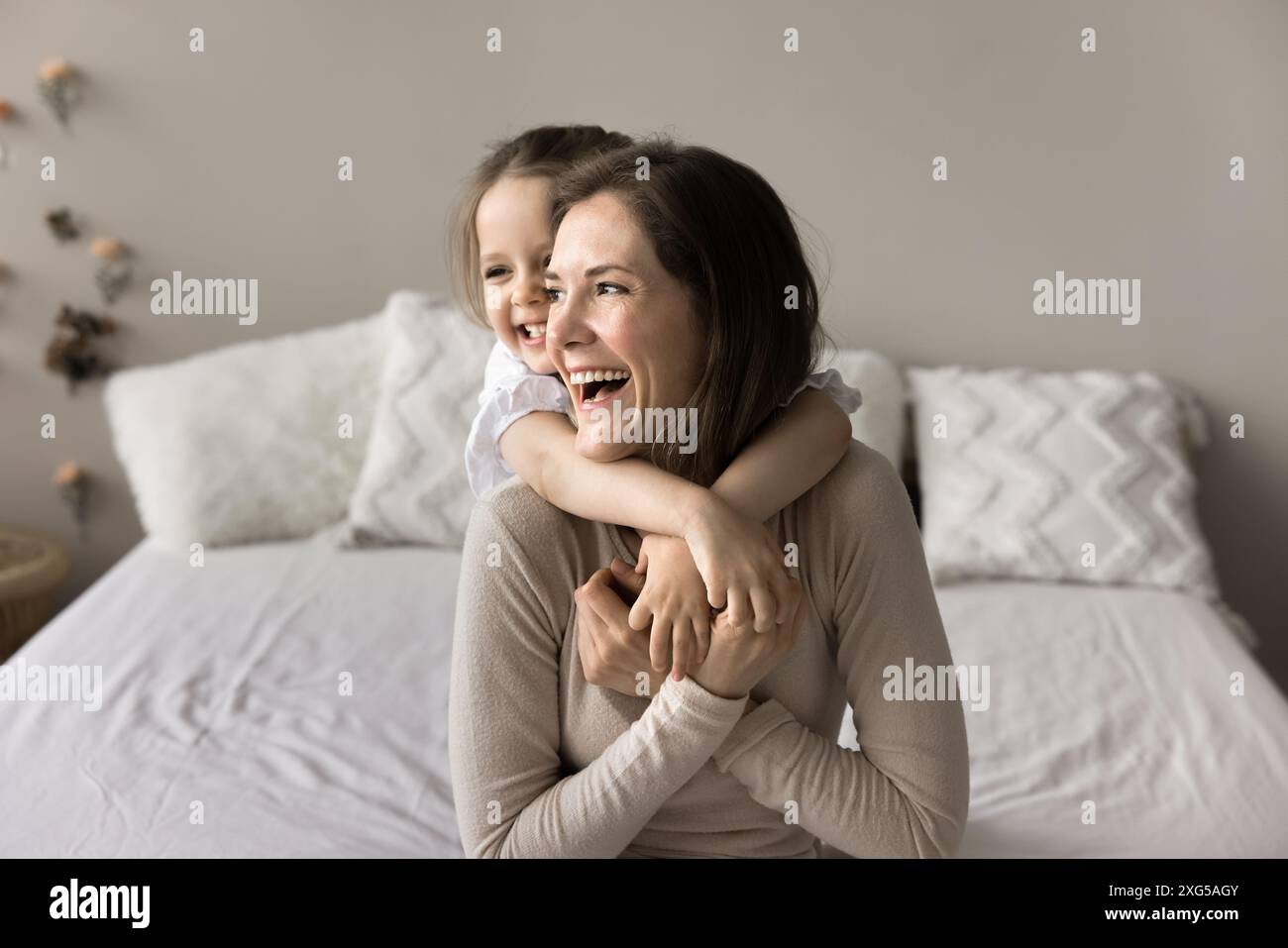 In cozy bedroom laughing awakened daughter cuddling from her mother ...