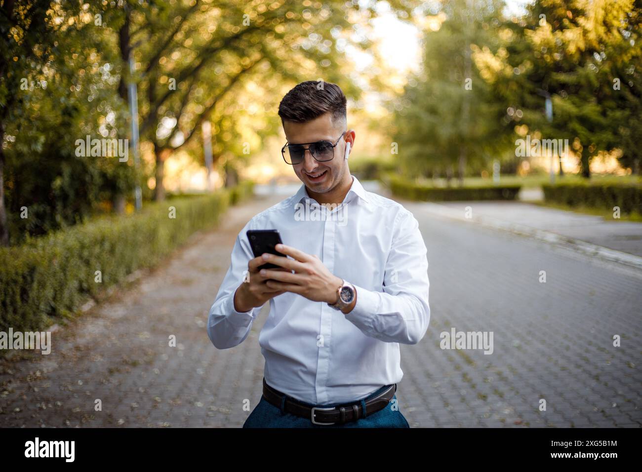 A man wearing a white shirt and blue pants is standing and staring ...