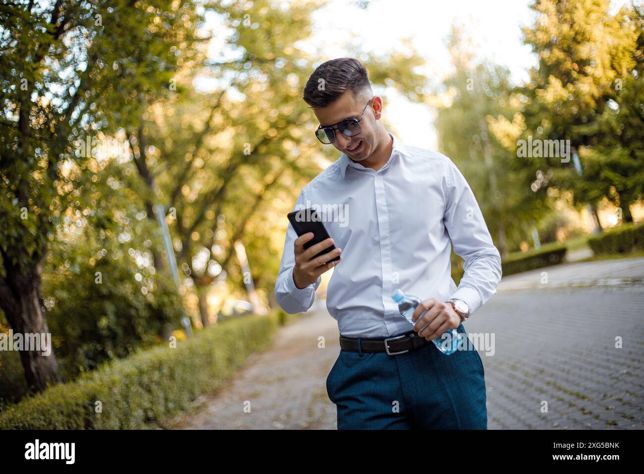A man dressed in a white shirt and blue pants is standing and looking ...