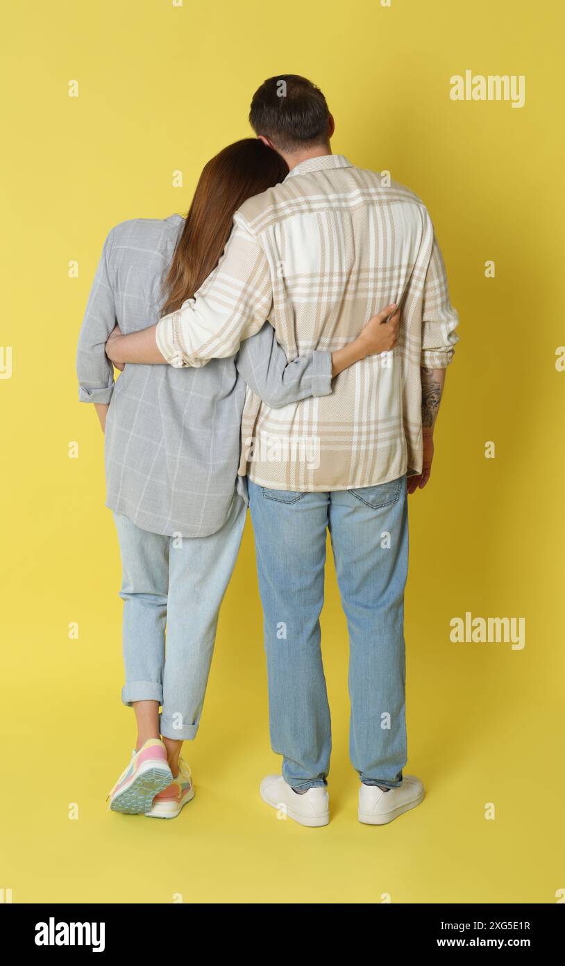 Cute couple hugging on yellow background, back view Stock Photo - Alamy