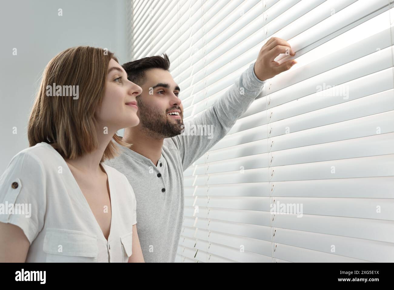 Young couple near window blinds at home Stock Photo - Alamy